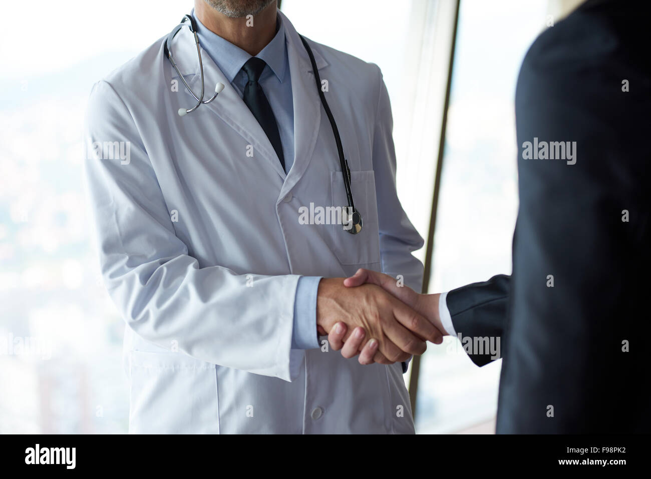 doctor handshake with a patient at doctors bright modern office in ...