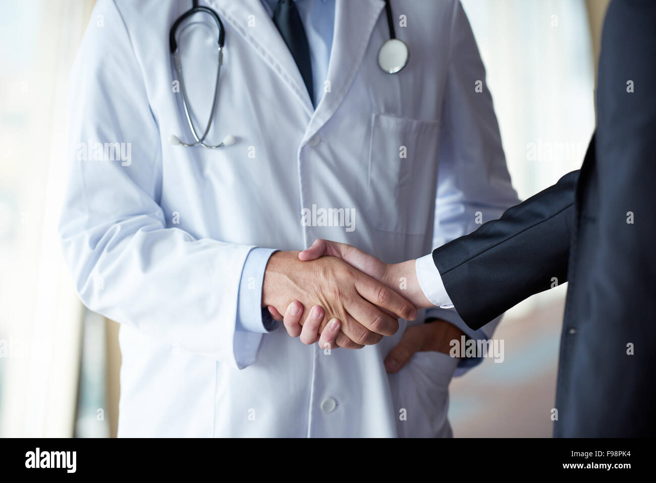 doctor handshake with a patient at doctors bright modern office in ...