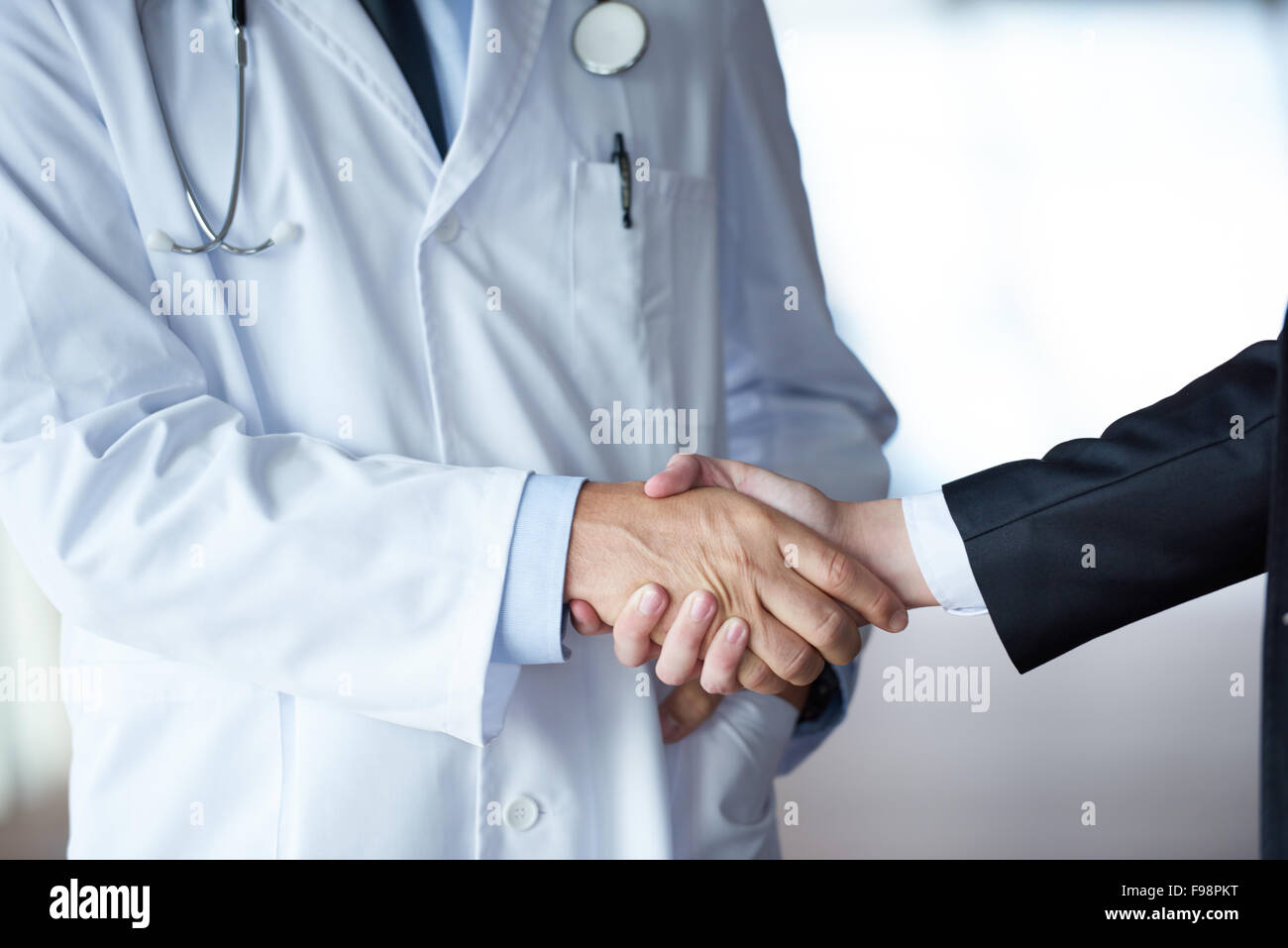 doctor handshake with a patient at doctors bright modern office in ...