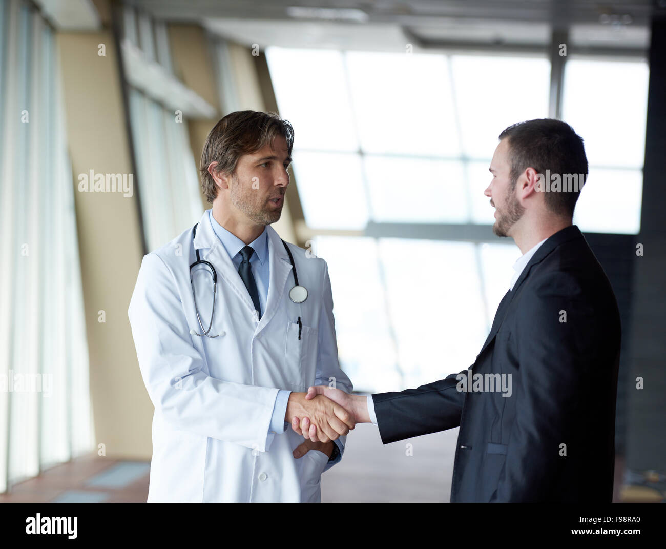 doctor handshake with a patient at doctors bright modern office in ...