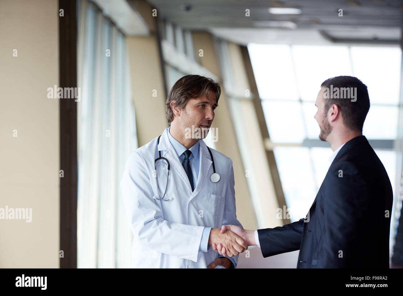 doctor handshake with a patient at doctors bright modern office in ...