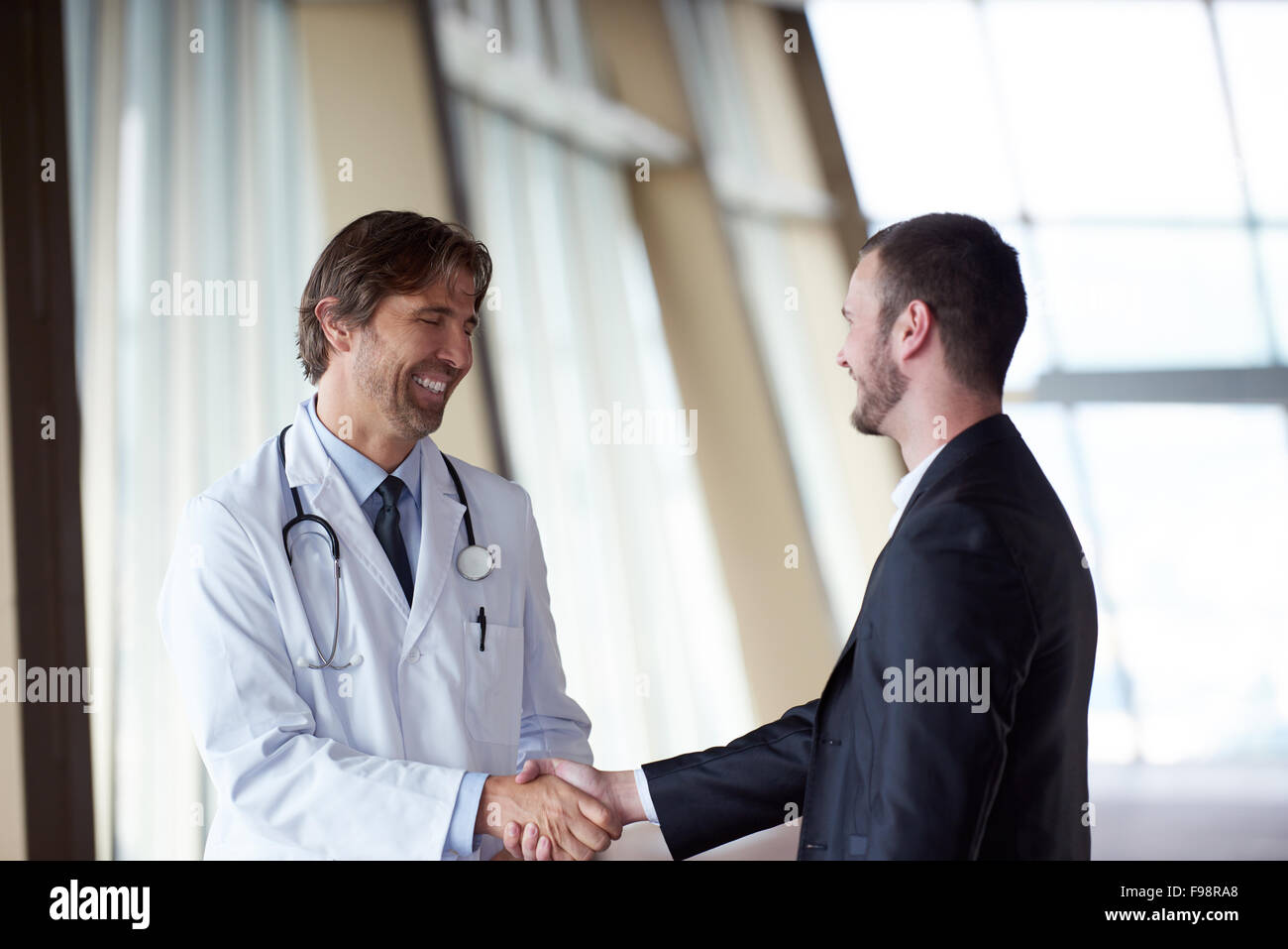 doctor handshake with a patient at doctors bright modern office in ...