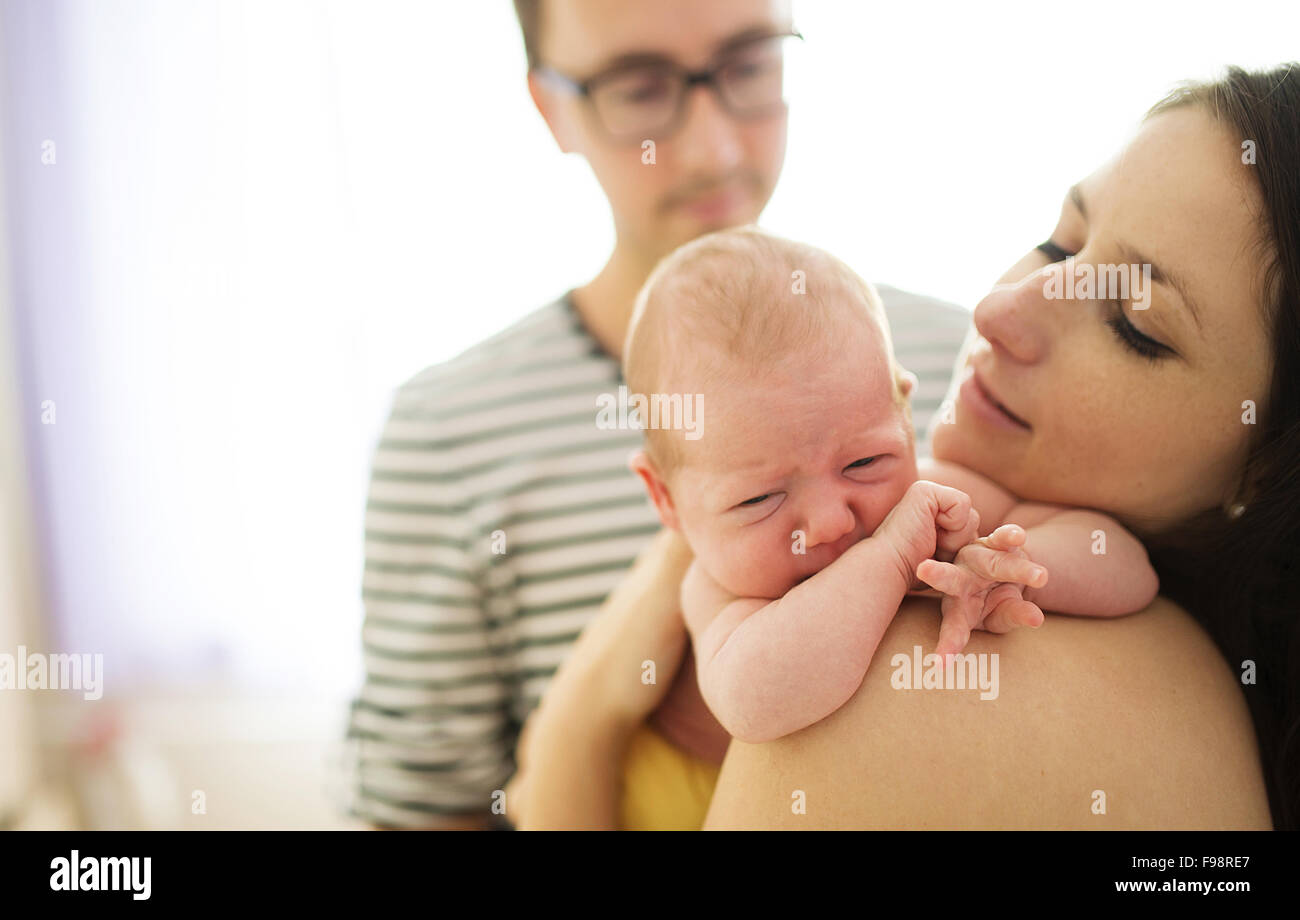 Happy young parents with their crying newborn baby girl at home Stock ...