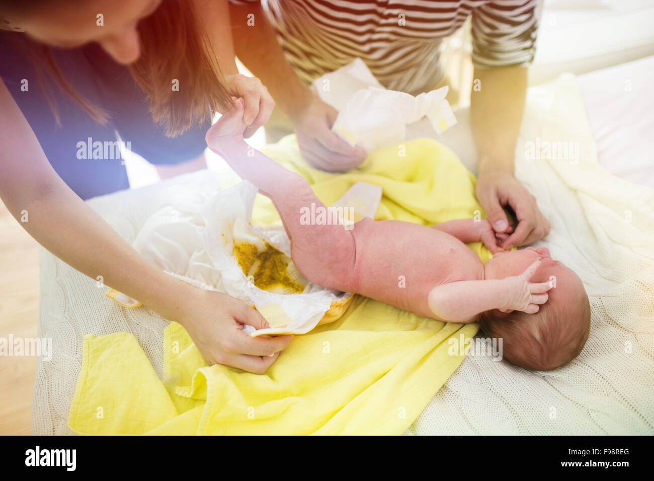Parents changing babby poop nappy. They are on the bed at home Stock ...