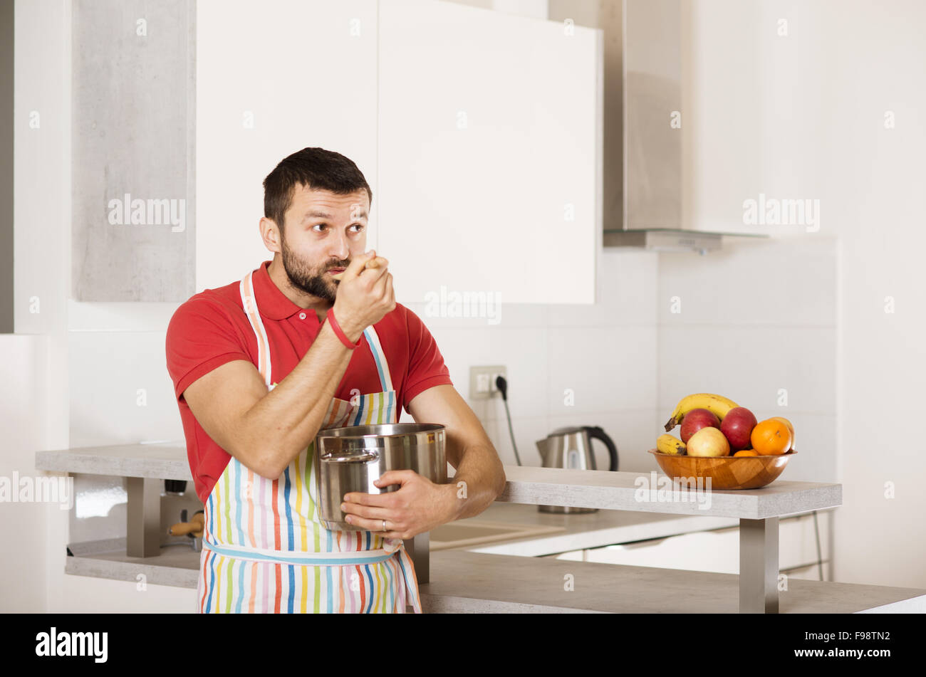 Young man with apron is cooking in the kitchen Stock Photo - Alamy