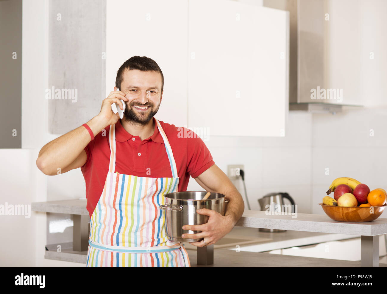 Young man with apron is cooking in the kitchen Stock Photo - Alamy
