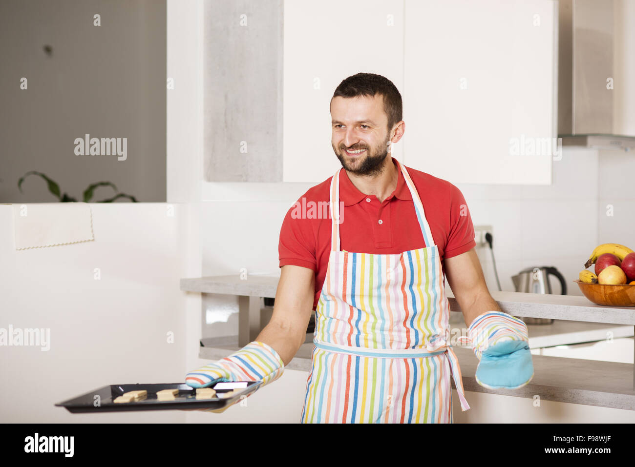 Young man with apron is cooking in the kitchen Stock Photo - Alamy
