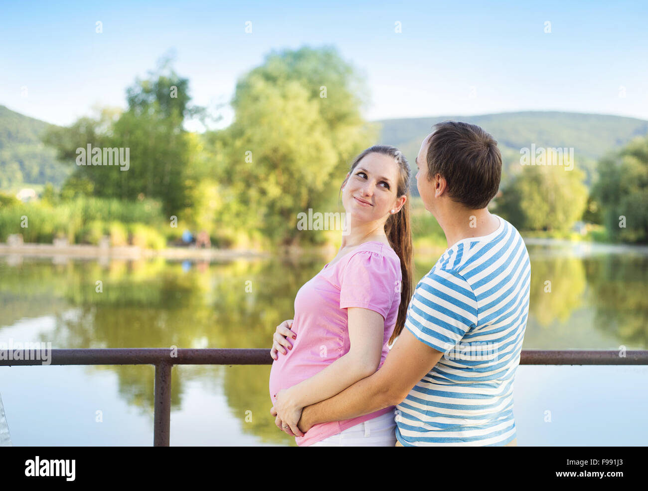 Happy young pregnant couple hugging in nature Stock Photo - Alamy