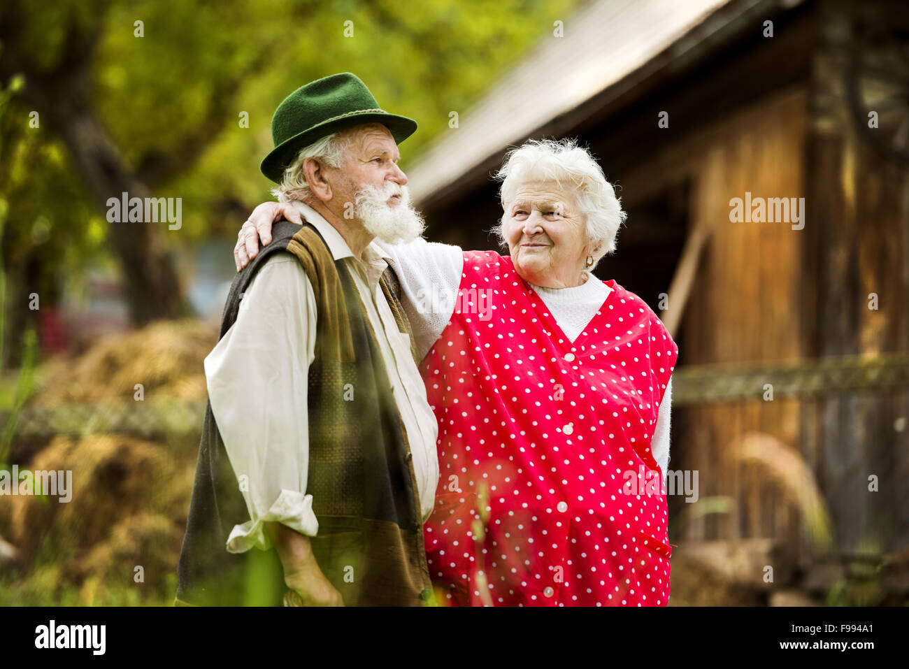 Outdoor portrait of old farmers couple standing by their farmhouse ...