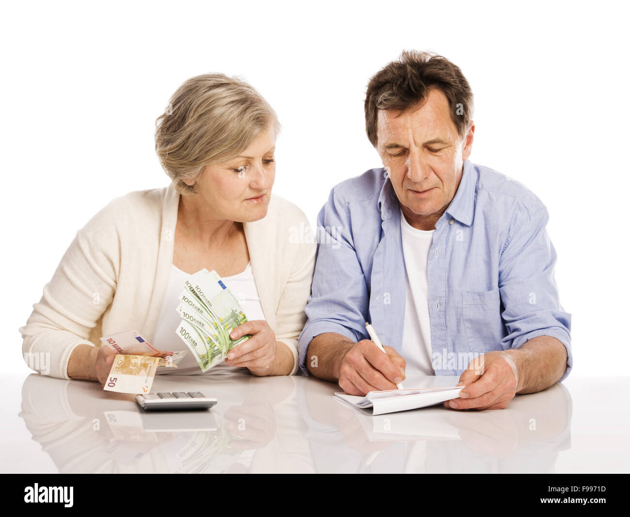 Senior couple counting money at the table, isolated on white background ...