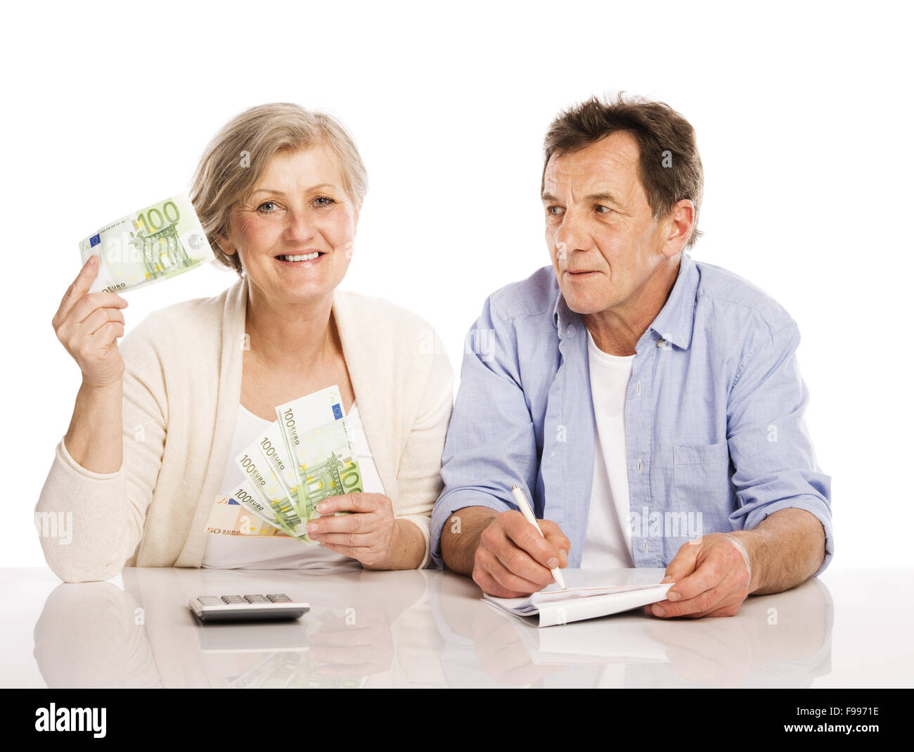 Senior couple counting money at the table, isolated on white background ...