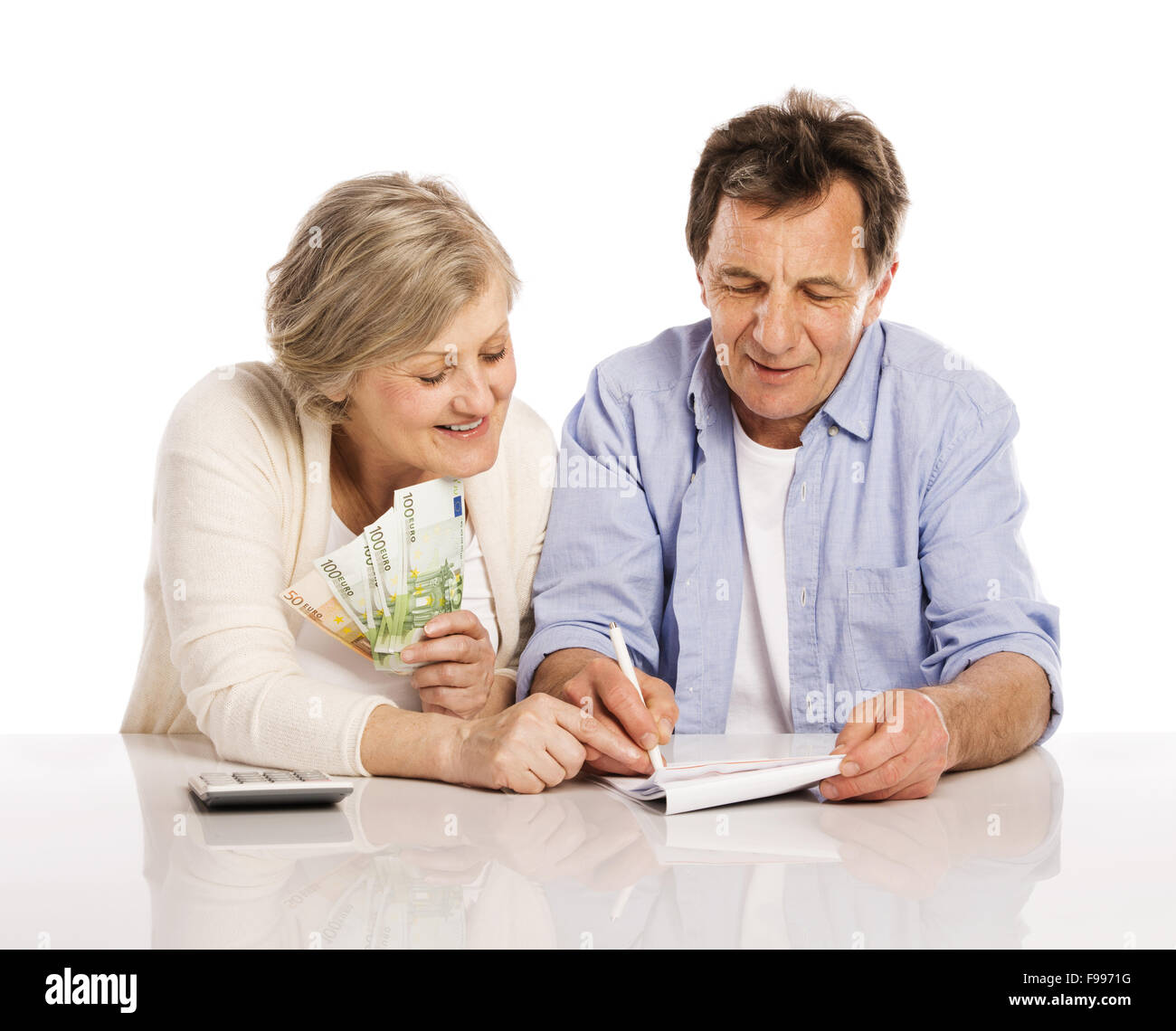 Senior couple counting money at the table, isolated on white background ...