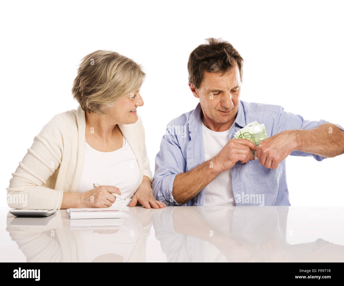 Senior couple counting money at the table, isolated on white background ...
