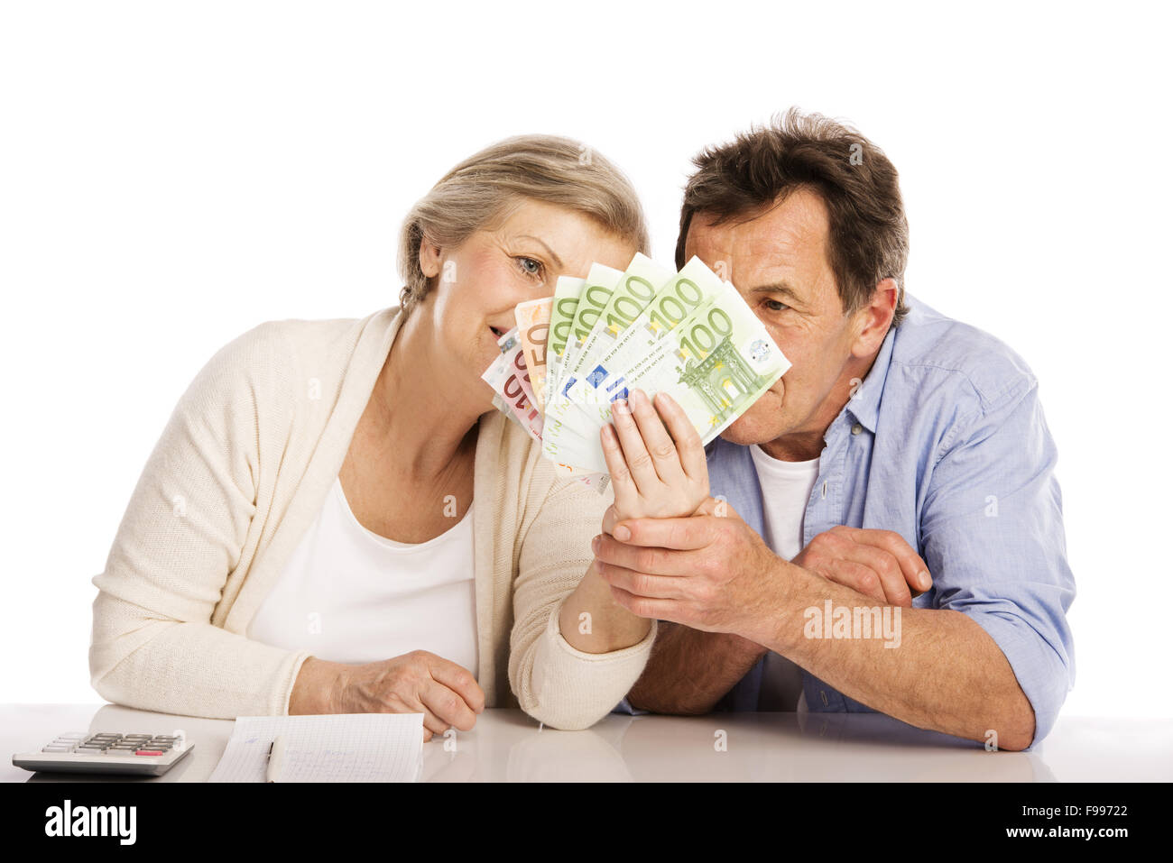 Senior couple counting money at the table, isolated on white background ...
