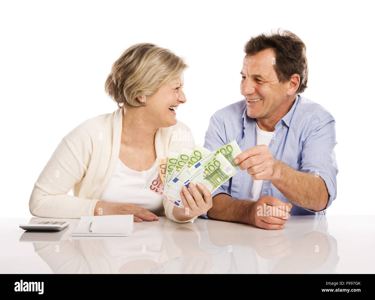 Senior couple counting money at the table, isolated on white background ...