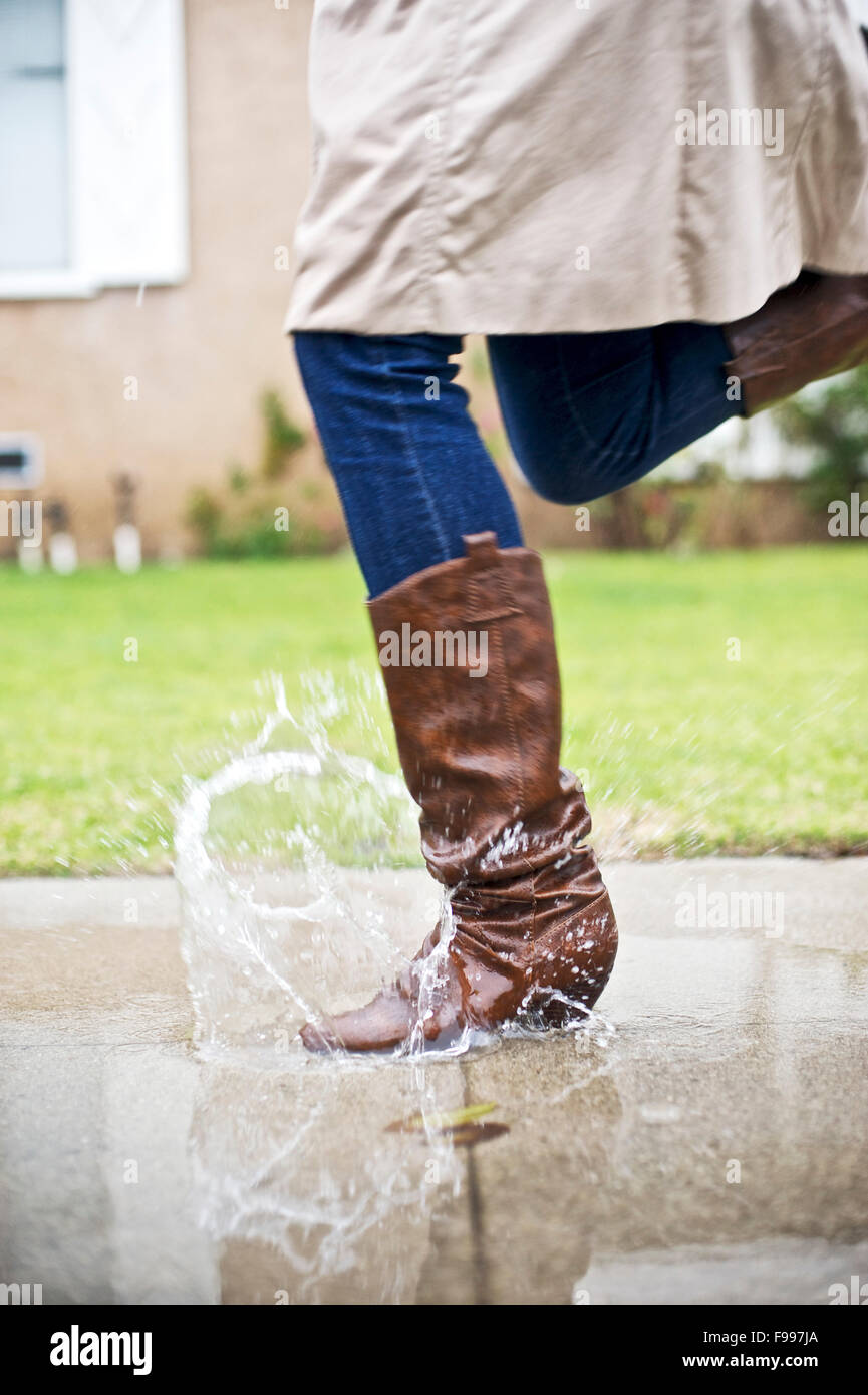 A foot splashes into a puddle while running along a sidewalk during a ...