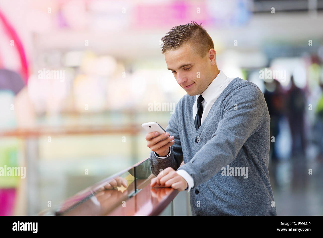 Handsome young man in shopping mall using mobile phone Stock Photo - Alamy