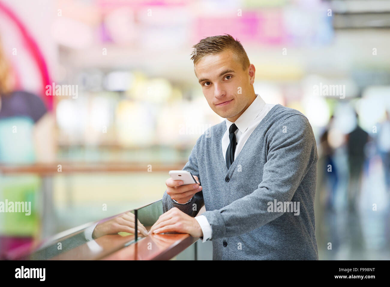 Handsome young man in shopping mall using mobile phone Stock Photo - Alamy