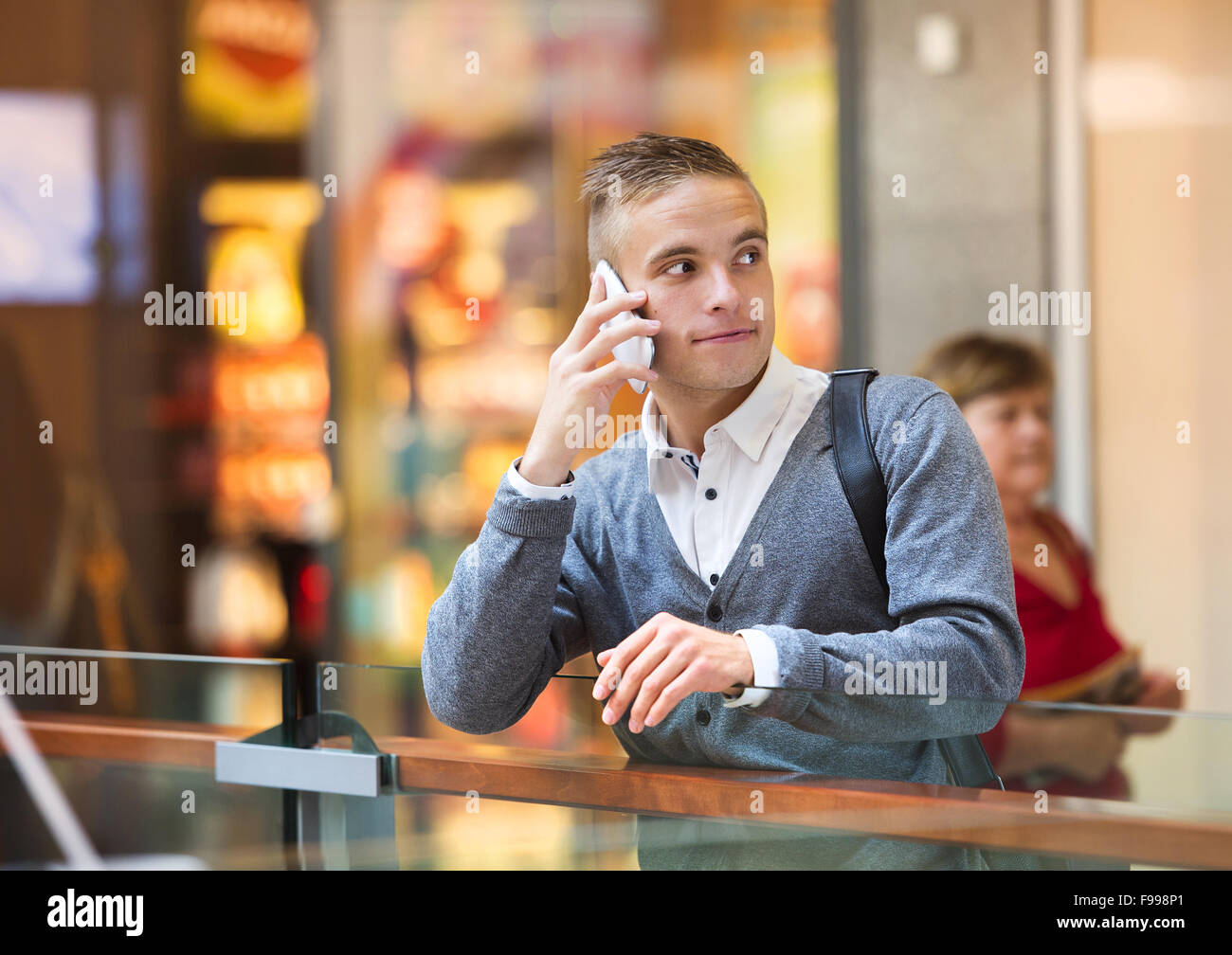 Handsome young man in shopping mall using mobile phone Stock Photo - Alamy