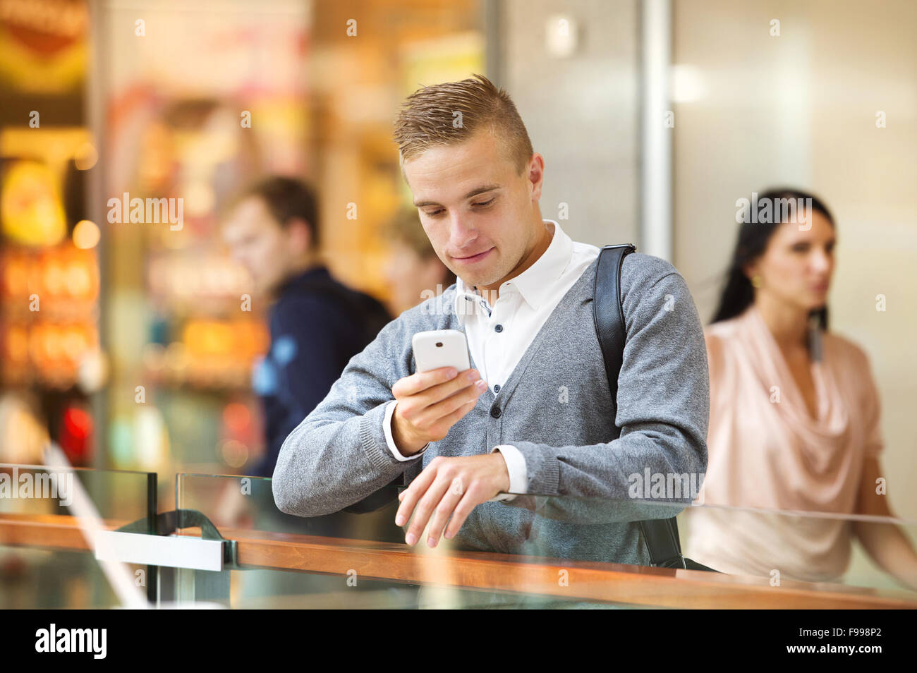 Handsome young man in shopping mall using mobile phone Stock Photo - Alamy