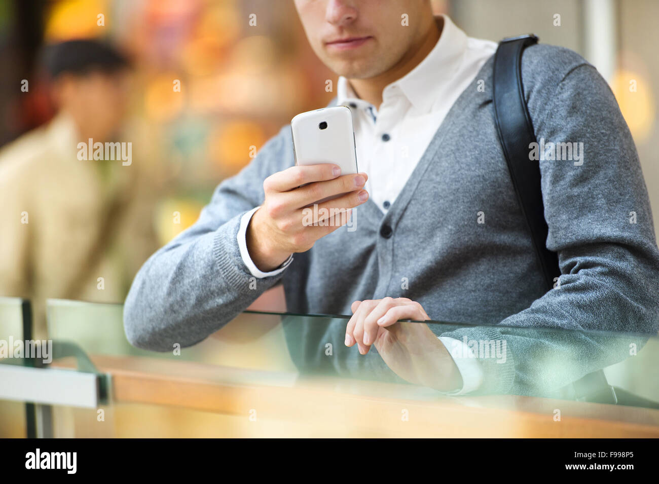 Handsome young man in shopping mall using mobile phone Stock Photo - Alamy