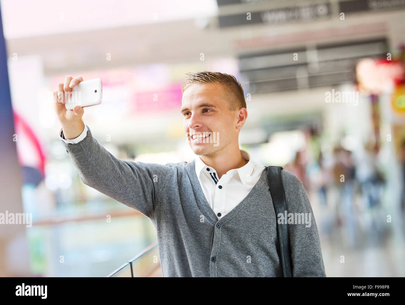Handsome young man in shopping mall using mobile phone Stock Photo - Alamy