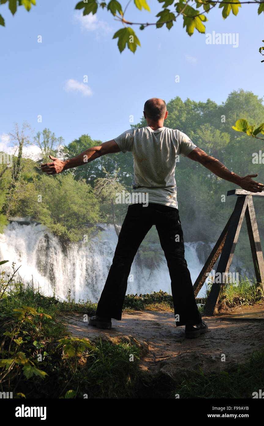 standing man with wide opened arms with waterfalls in background and ...