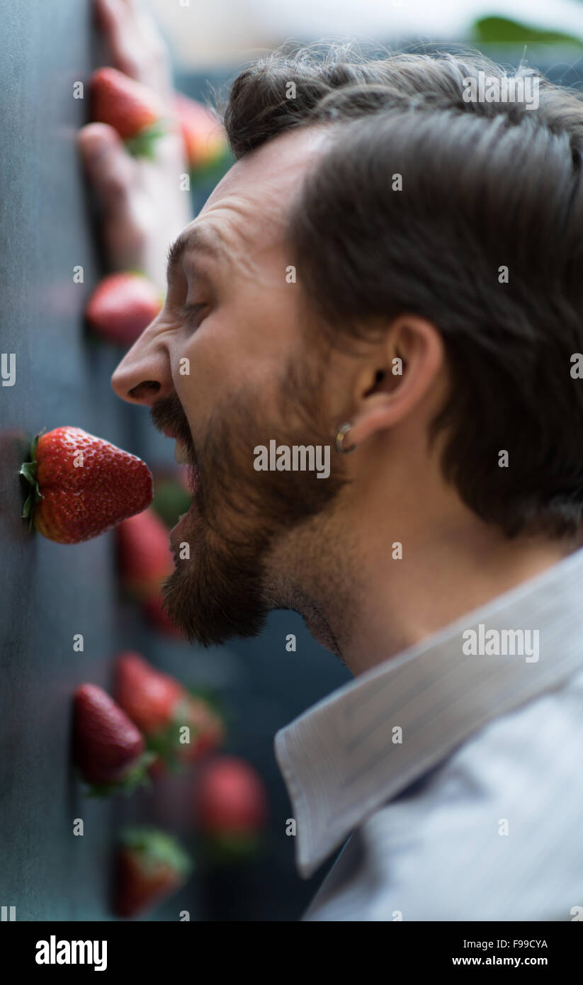 Man eating strawberry from stone wall - surreal photo Stock Photo - Alamy