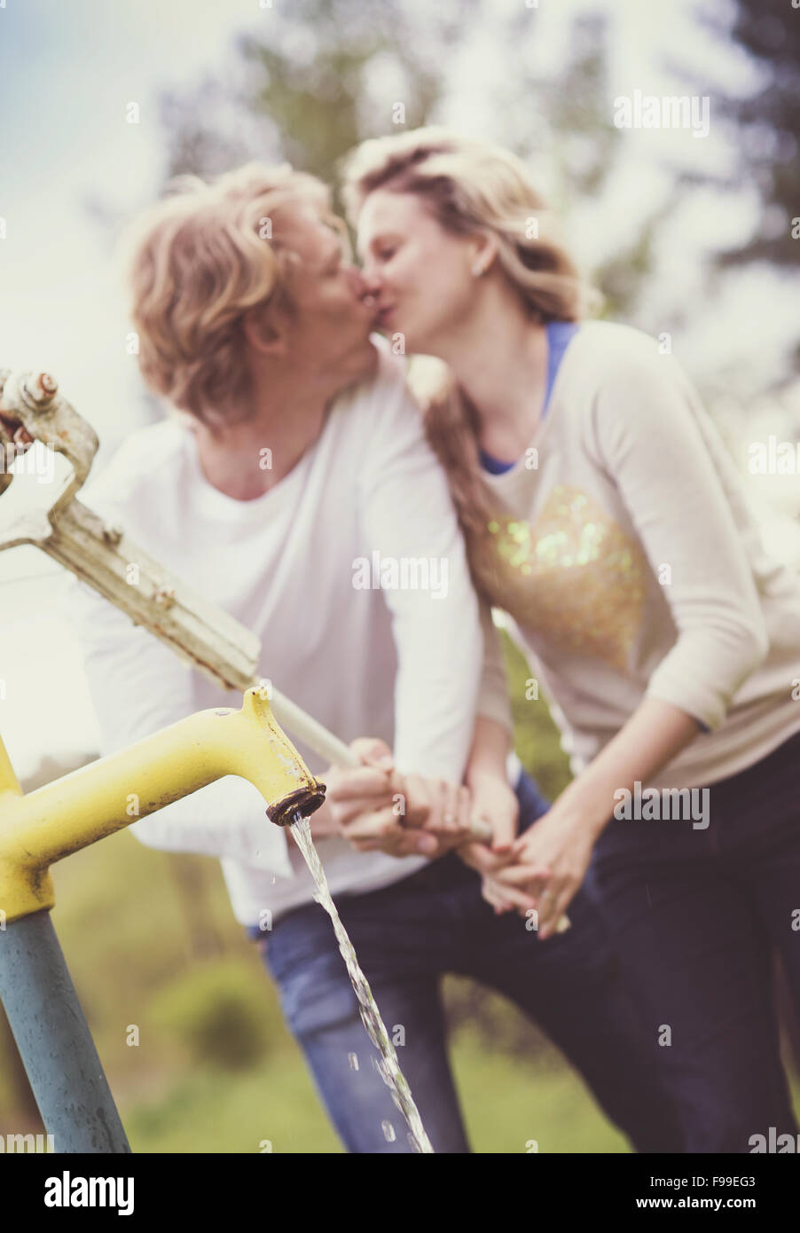 Spring outdoor portrait of young happy couple pumping water from water ...