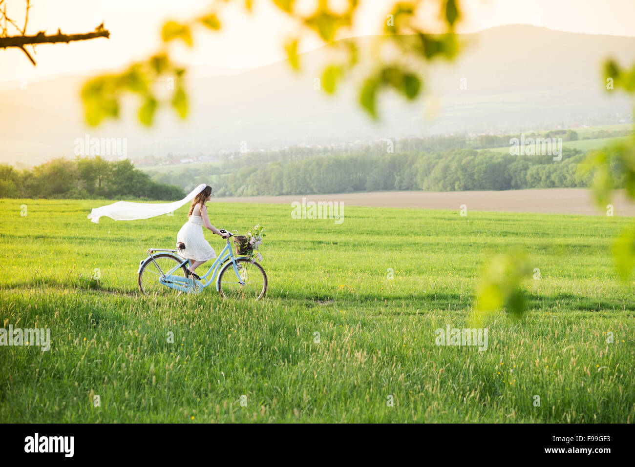 Pretty young bride riding retro bike in green meadow Stock Photo - Alamy