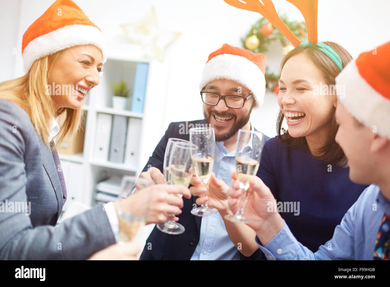 Joyful colleagues toasting with champagne at corporate Christmas party ...