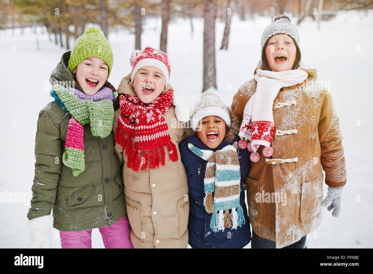 Happy children in winter-wear looking at camera in natural environment ...