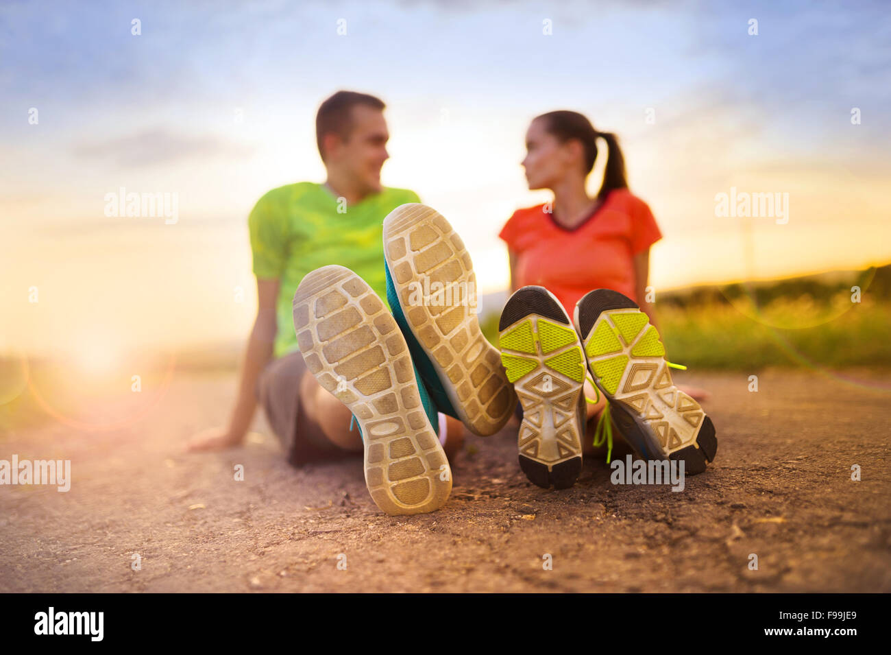 Cross-country trail running couple stretching and exercising at sunset ...