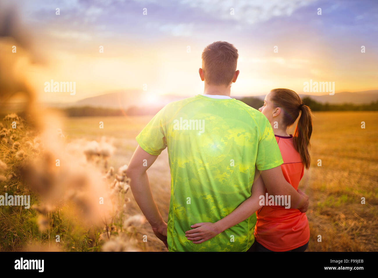 Cross-country trail running couple relaxing and watching the sunset ...