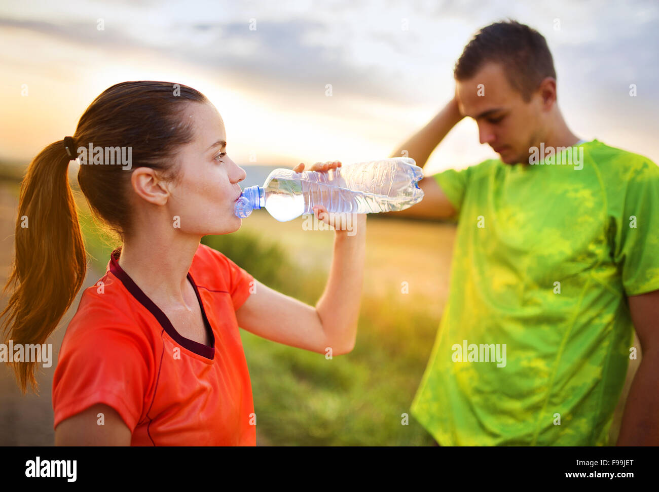 Cross-country trail running couple having water break at sunset Stock ...