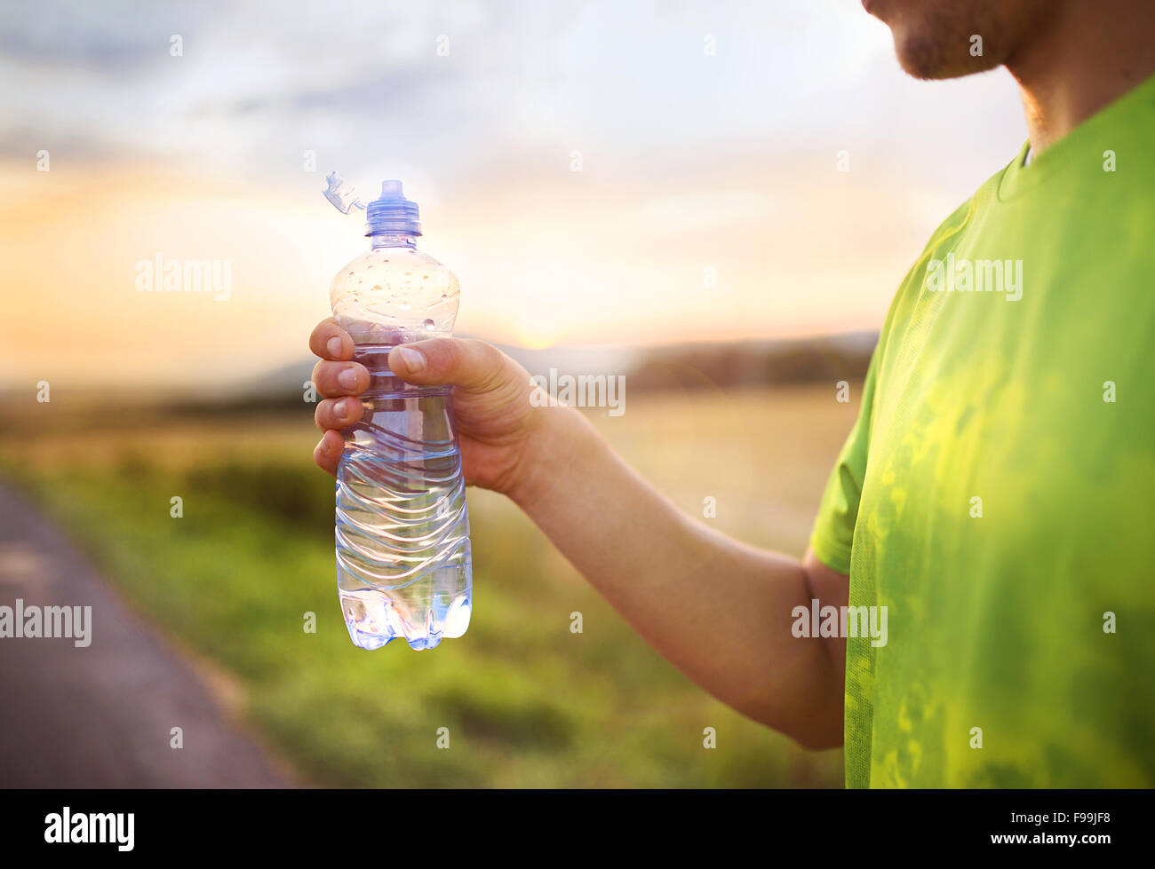 Cross-country trail running man having water break at sunset Stock ...