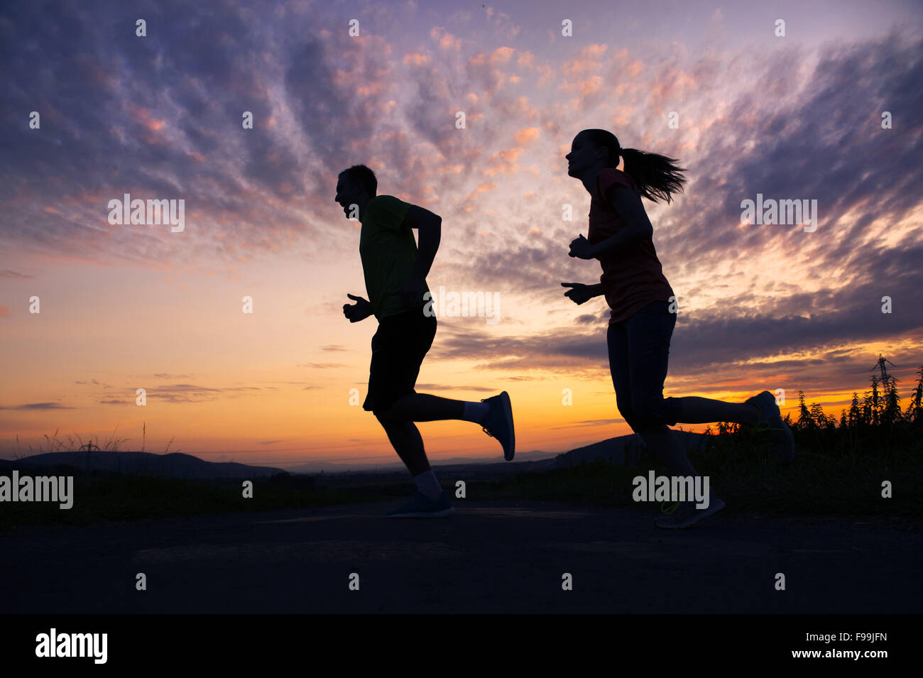 Silhouette of young couple running in sunset Stock Photo - Alamy