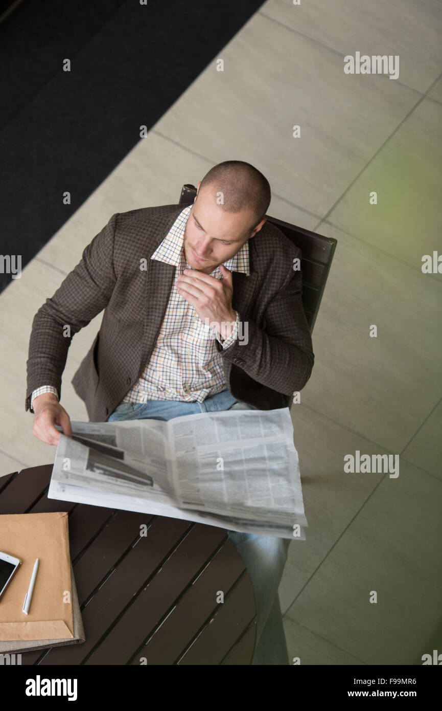 Handsome businessman or manager in office building reading newspaper ...