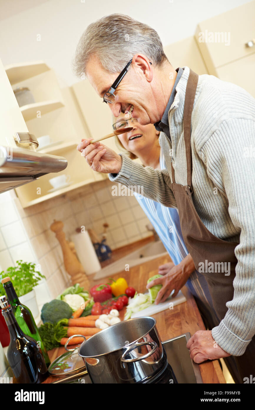 Two happy senior people cooking in the kitchen Stock Photo - Alamy