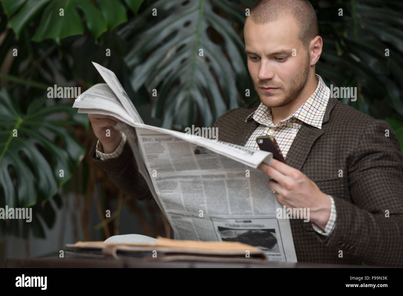 Businessman reading newspaper on chair at office building hall or cafe ...