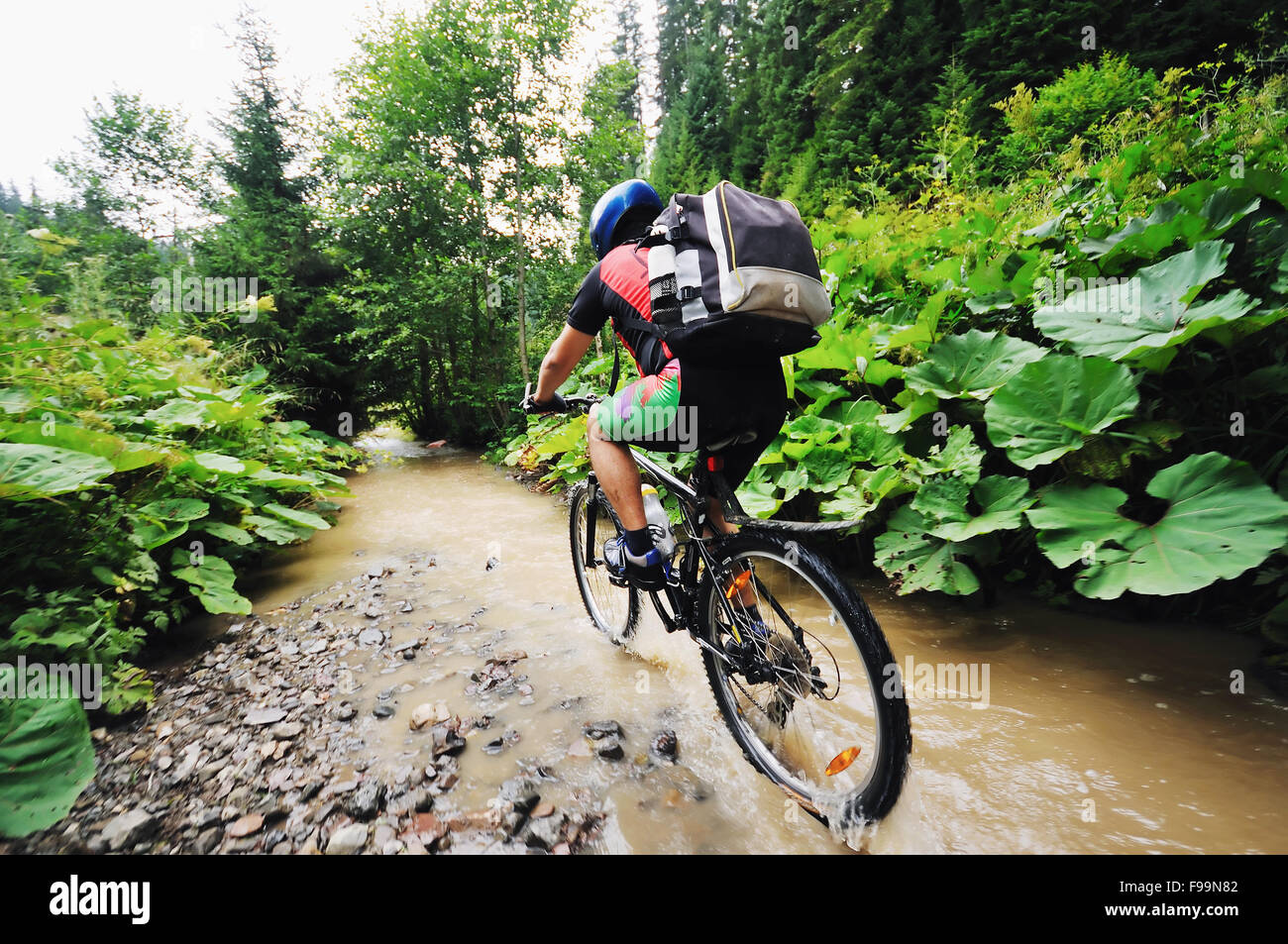 young man drive mountain bike over water river Stock Photo - Alamy