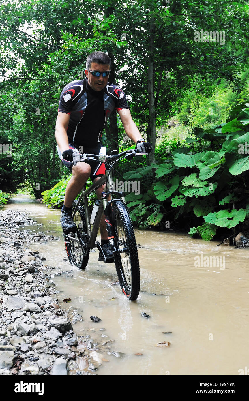 young man drive mountain bike over water river Stock Photo - Alamy