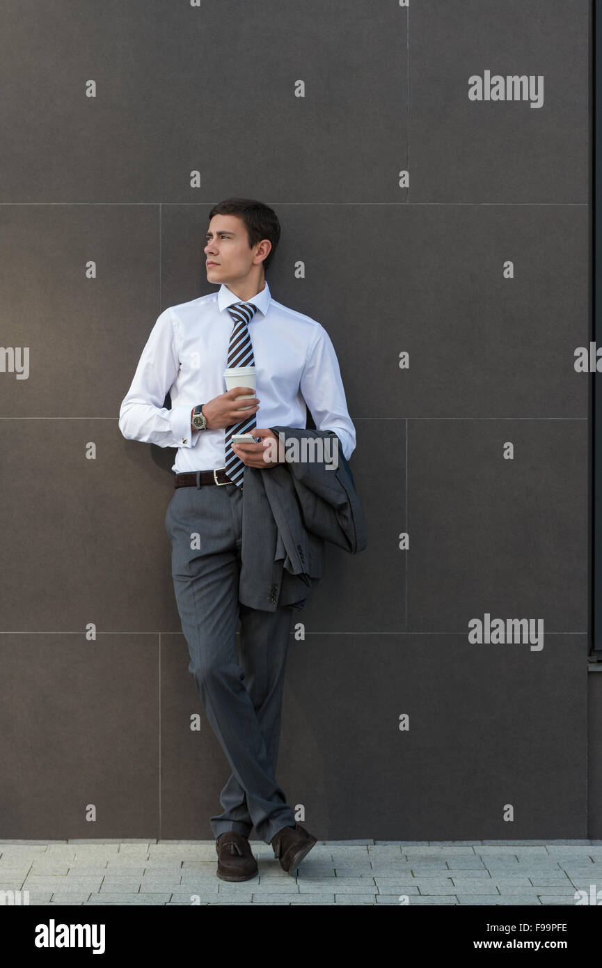 Businessman Leaning on Modern Office Building Wall With Coffee Using ...