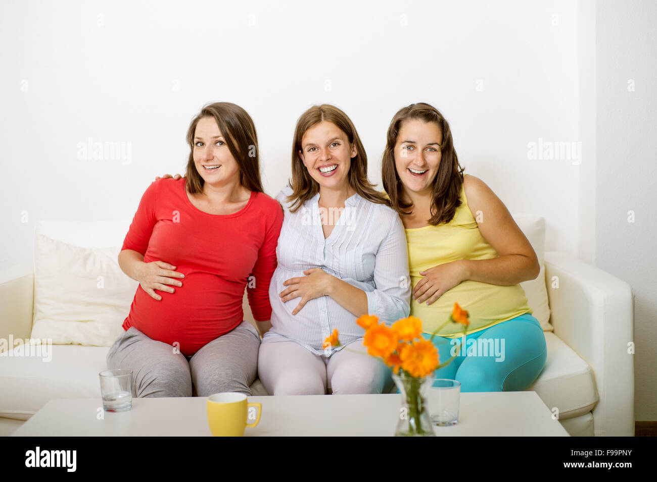 Three pregnant women sitting on sofa and posing Stock Photo - Alamy