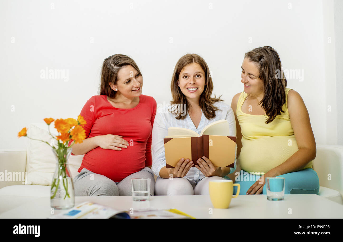 Three pregnant women sitting on sofa and posing Stock Photo - Alamy