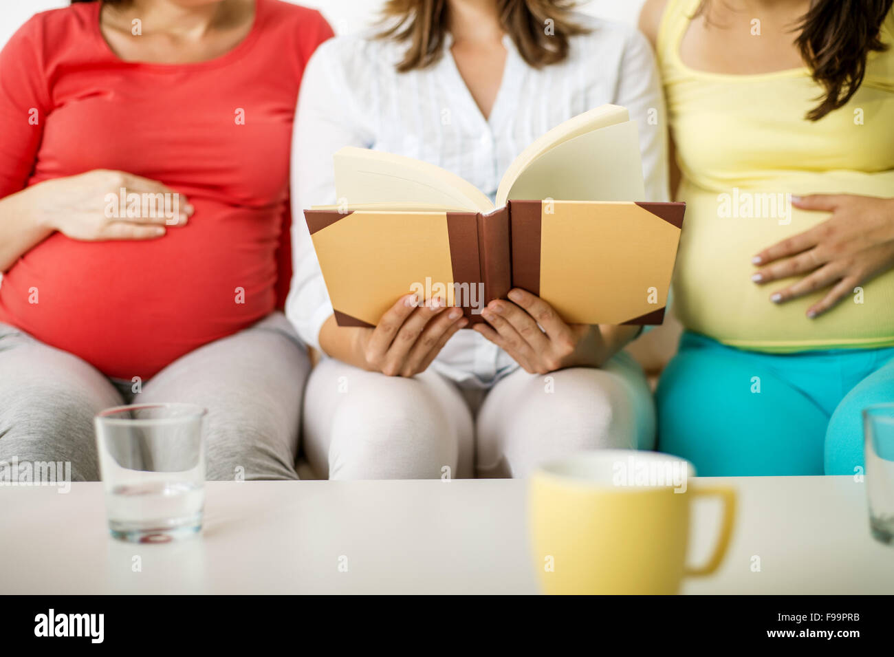 Three pregnant women sitting on sofa and posing Stock Photo - Alamy