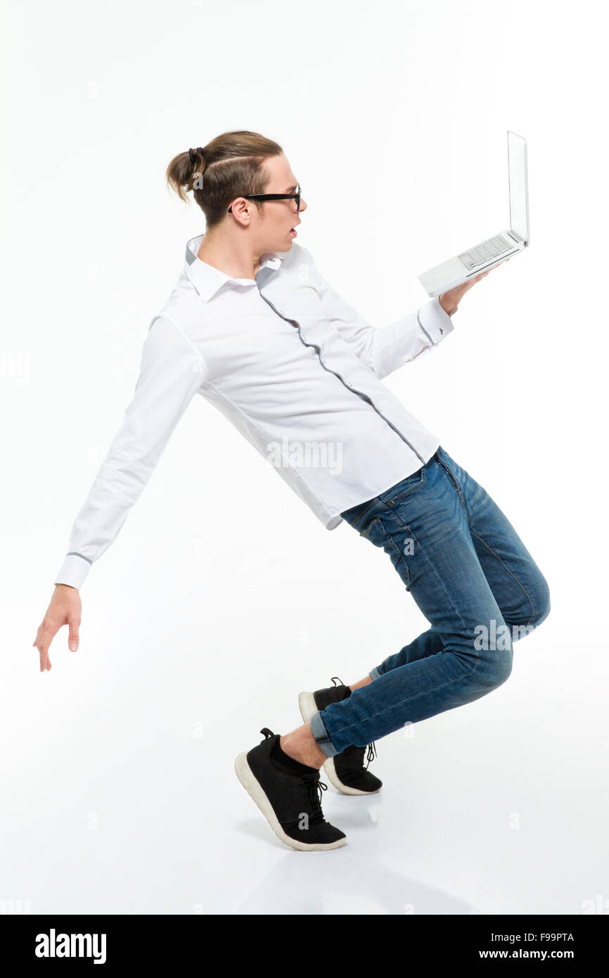 Full length portrait of a young casual man dancing with laptop computer ...