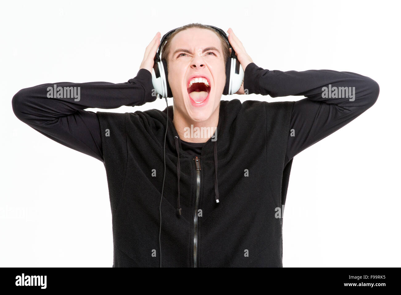 Portrait of a young angry man listening music in headphones and ...
