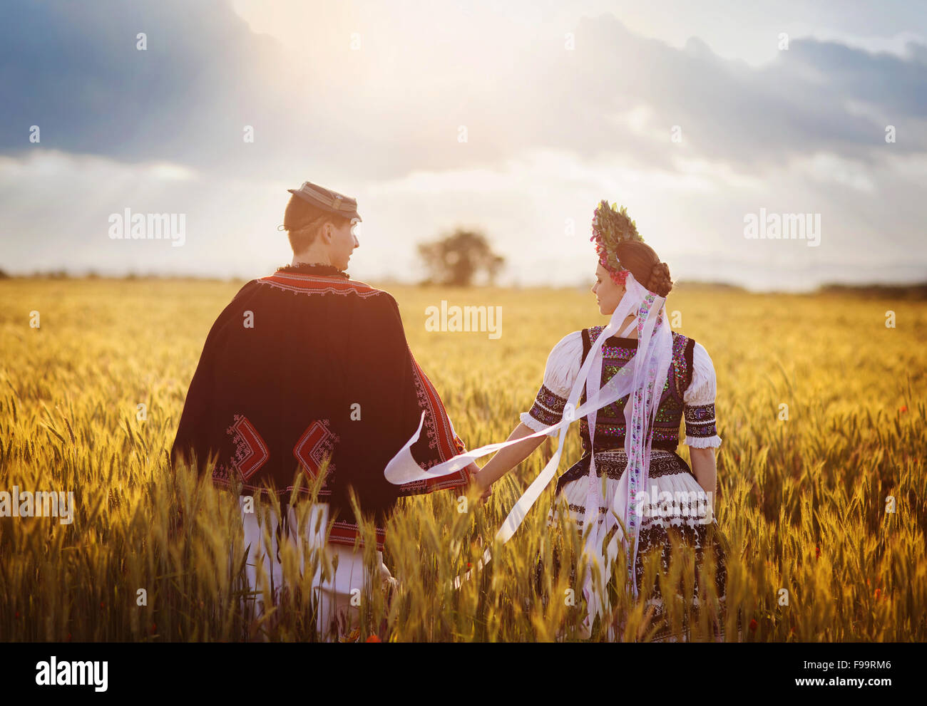 Love couple in sunset field. They wearing traditional Eastern Europe ...