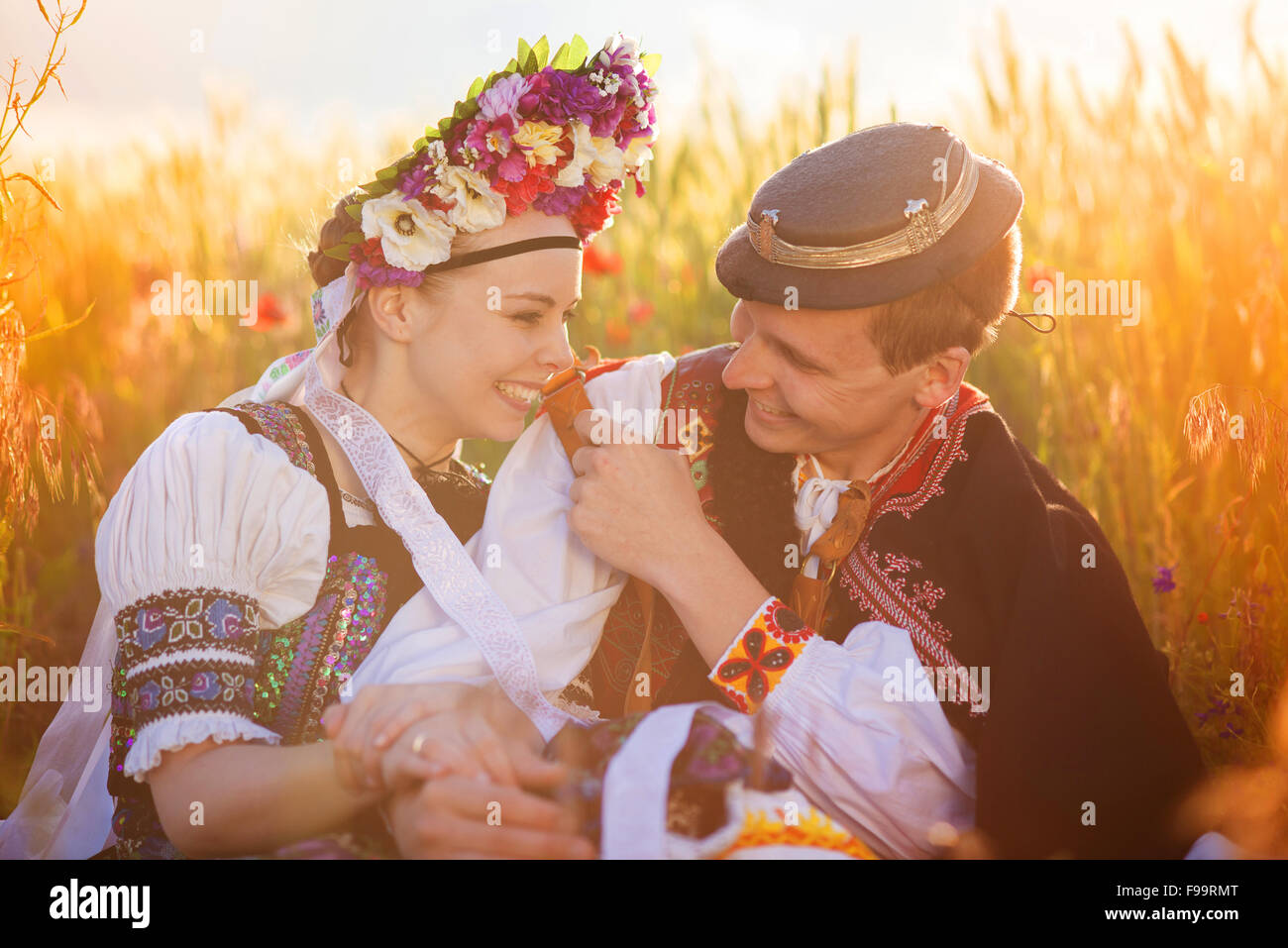 Love couple in sunset field. They wearing traditional Eastern Europe ...